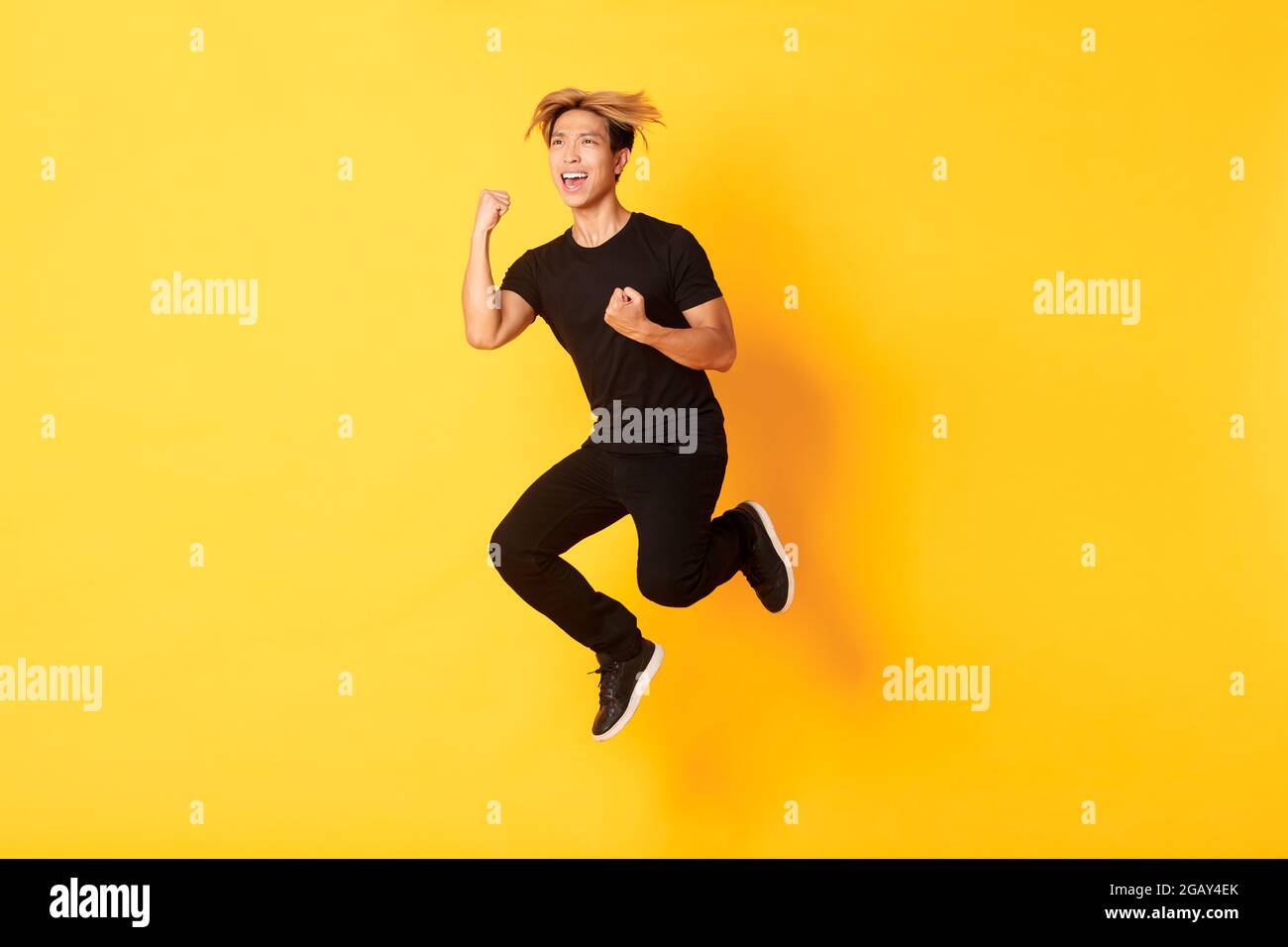 Full-length of happy attractive asian guy in black clothes jumping and ...