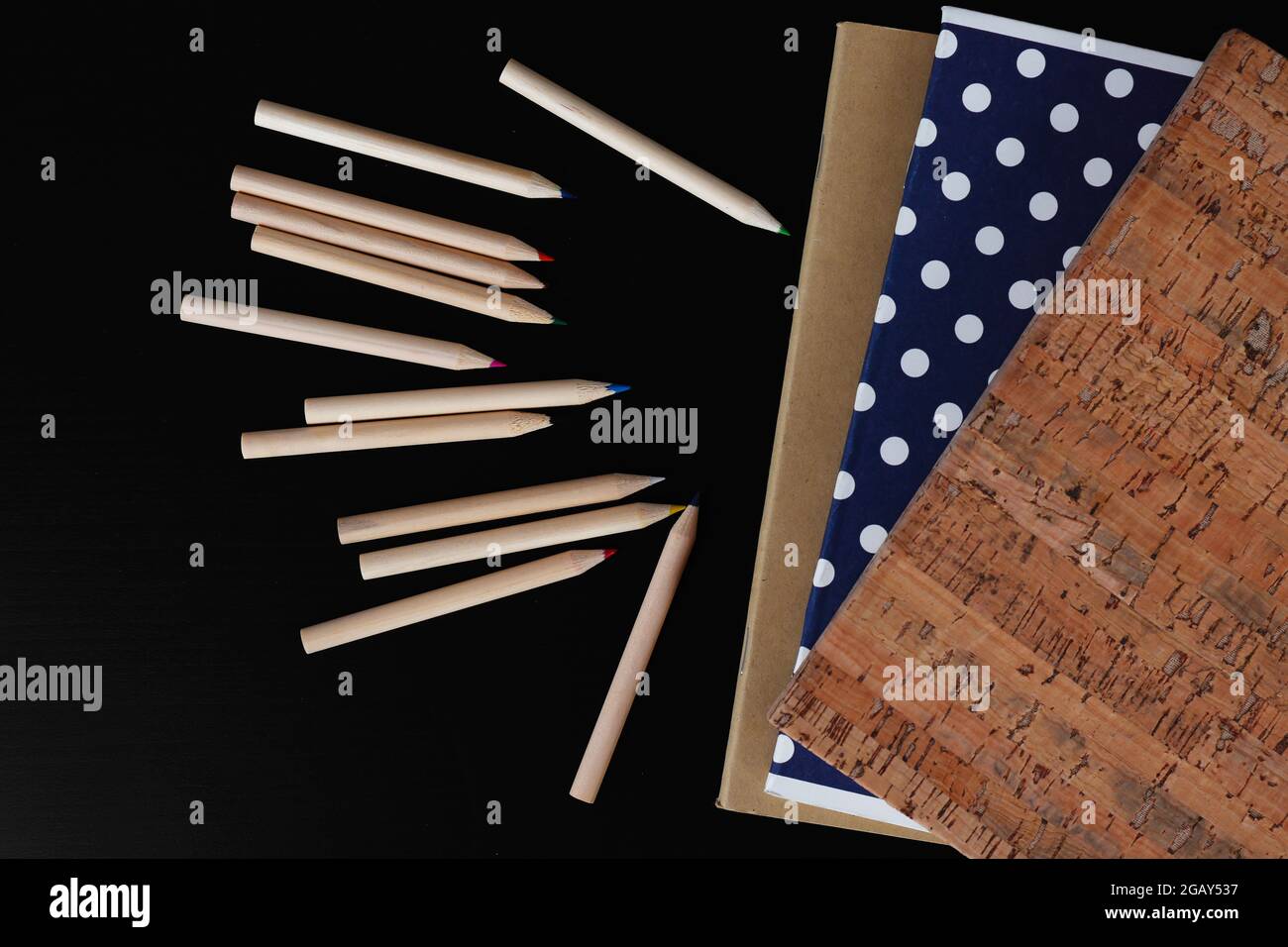 Notebooks with coloured pencils on black table Stock Photo - Alamy