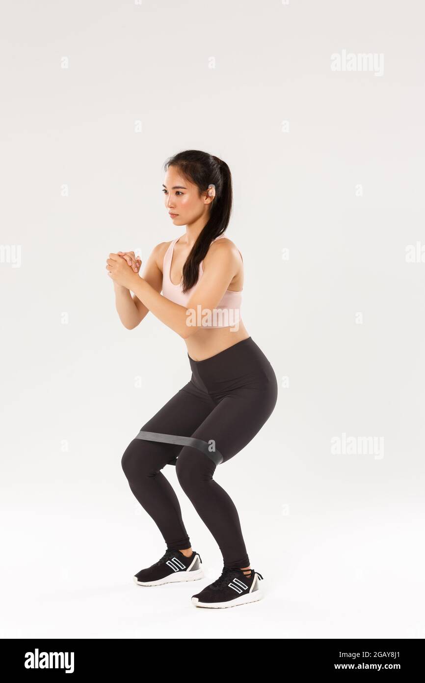Full length side view of focused slim asian girl doing fitness training, female athlete clasp ...