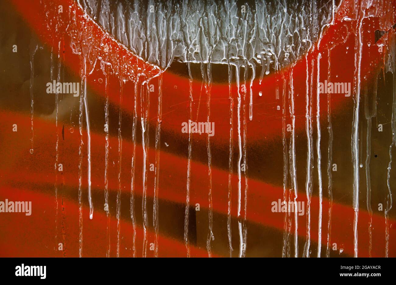 Red and white dripping paint on a window glass, vandalizec property ...