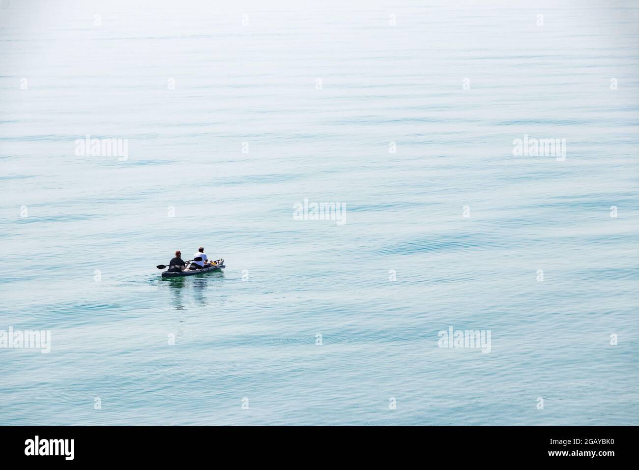 isolated boat with two rowers in the sea taken from the pier at ...
