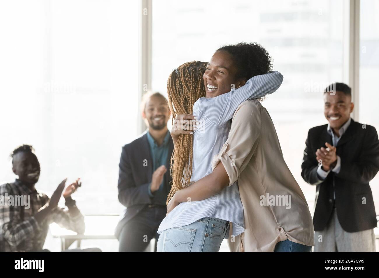 Happy young african ethnicity woman cuddling colleague Stock Photo - Alamy