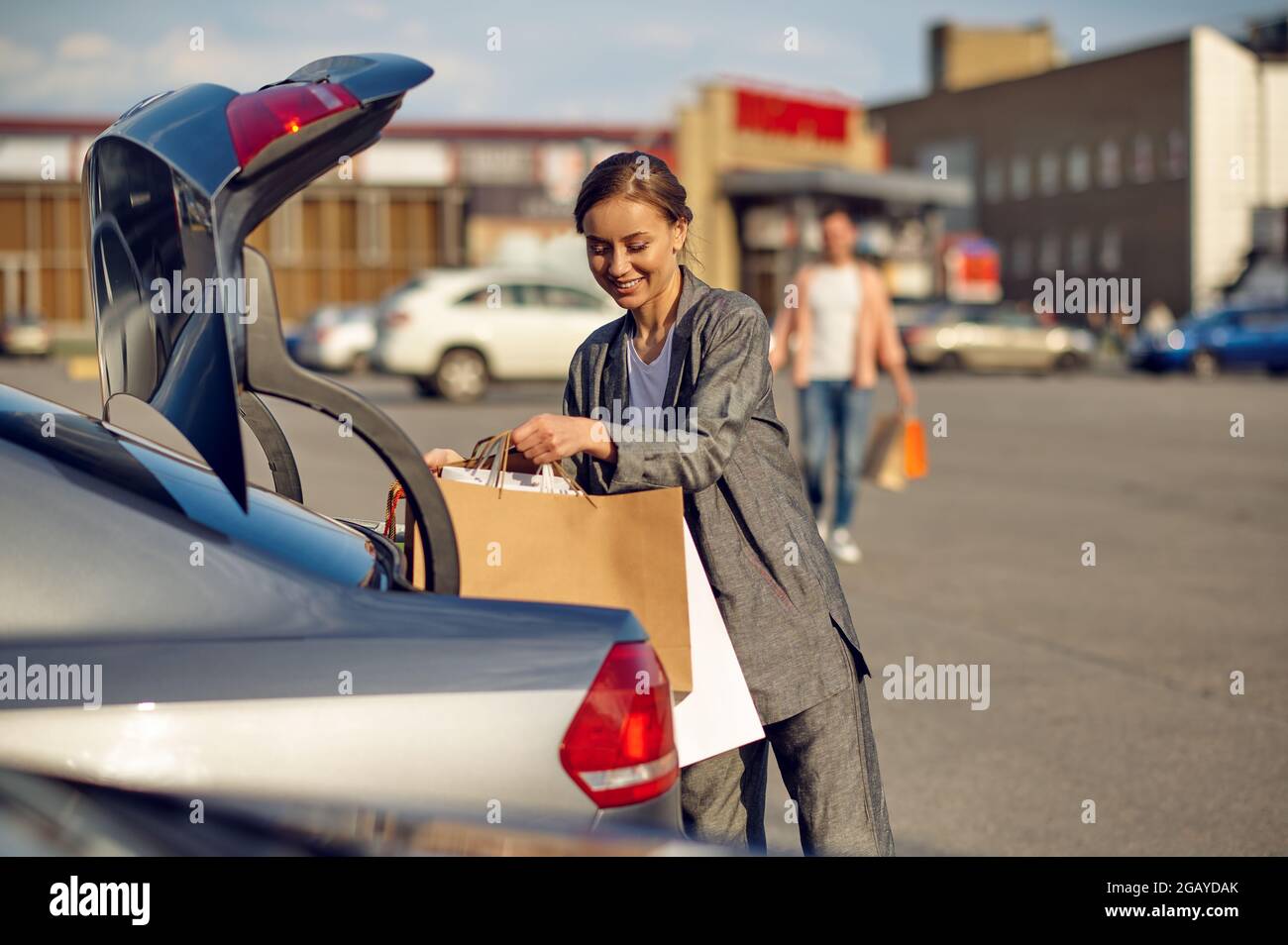 Woman puts her purchases in the trunk on parking Stock Photo - Alamy