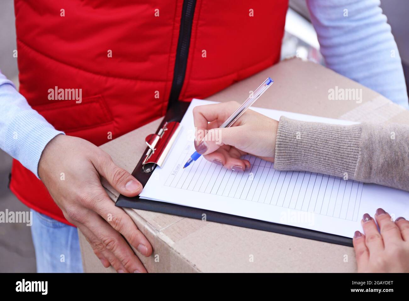 Female hand signing delivery form on the box, close-up Stock Photo - Alamy