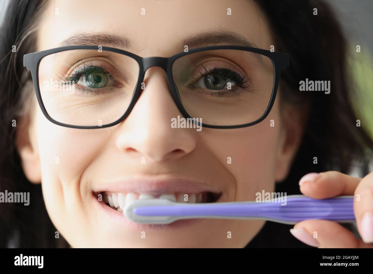 Portrait of young brunette brushing teeth with toothbrush Stock Photo ...