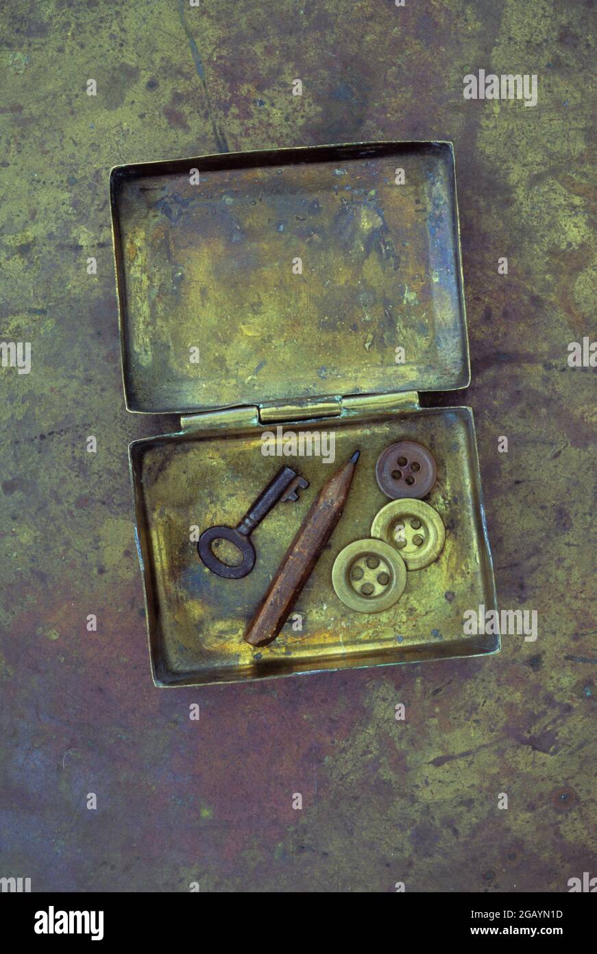 Tarnished brass tin containing old buttons and pencil and key Stock ...