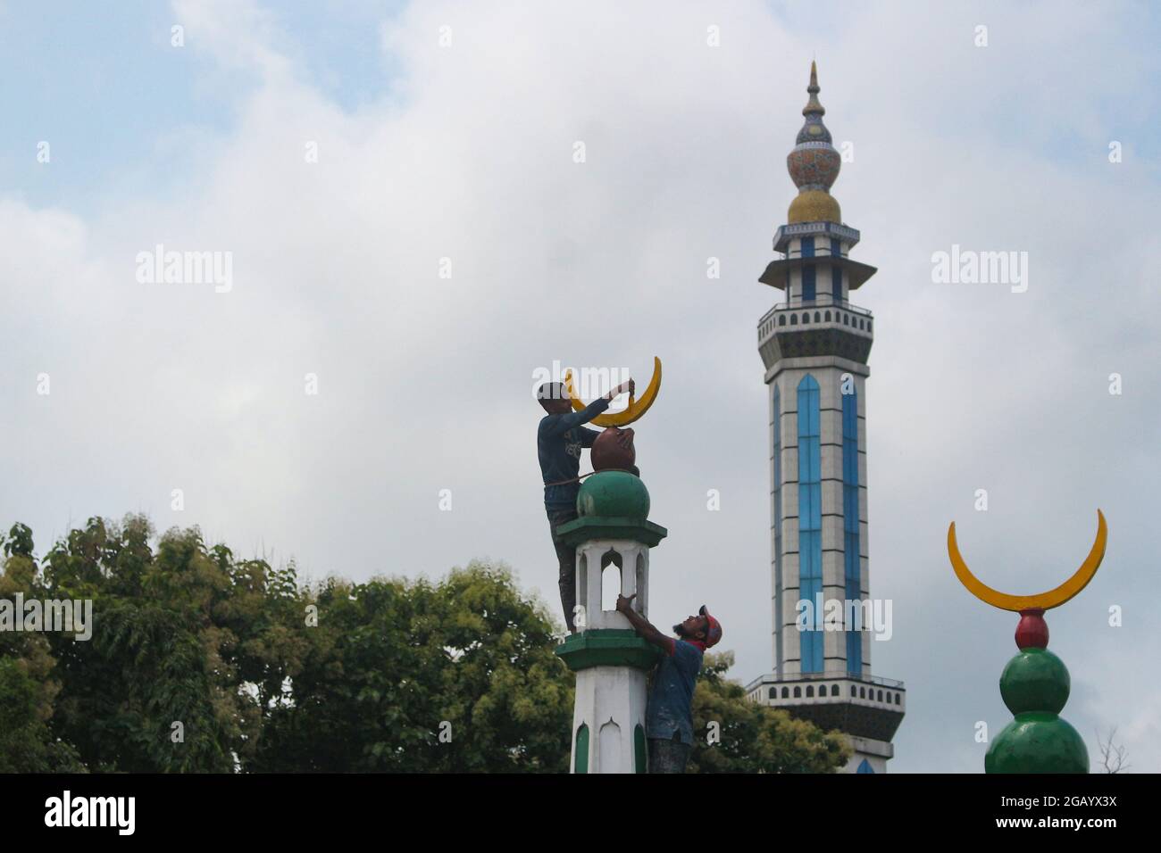 Workers paint the minaret of the gate of the Central Shahi Eidgah ...