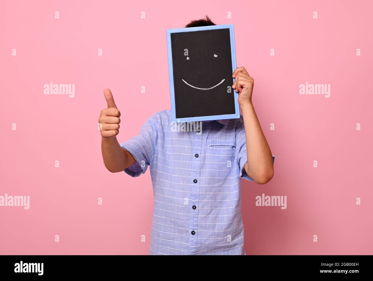 Unrecognizable school boy covers his face with a chalkboard with drawn ...