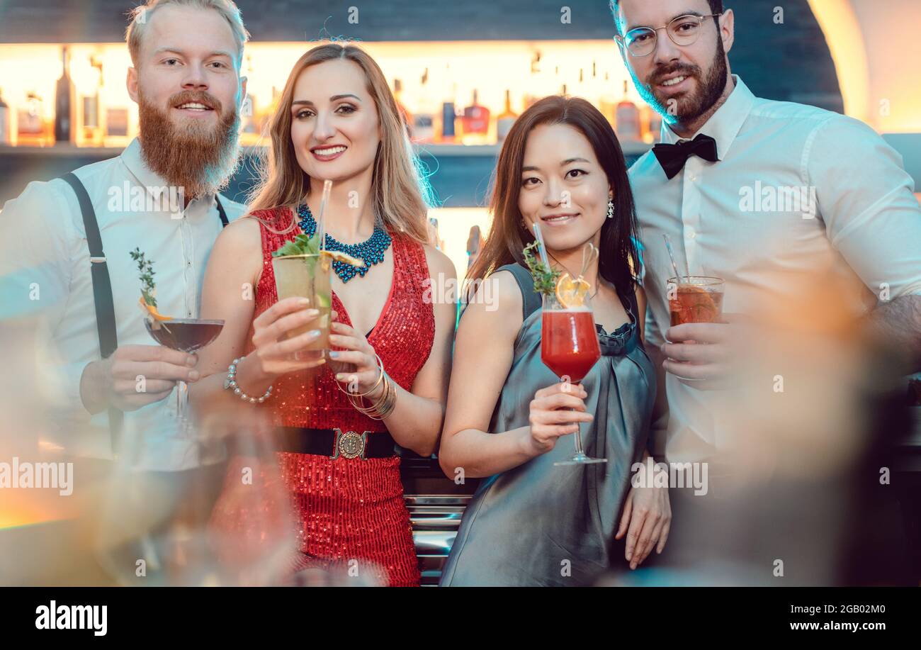 Young couple posing with cocktail glasses in bar Stock Photo - Alamy