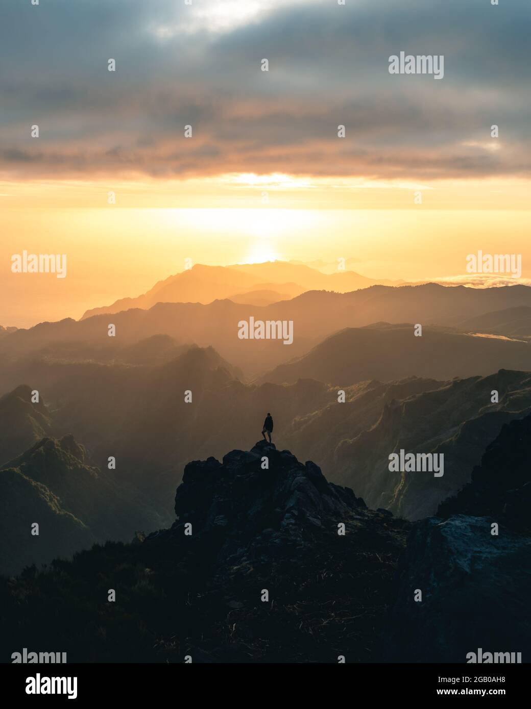 Man stands alone on the peak of rock during sunrise at Pico do Arieiro ... Man stands alone on the peak of rock during sunrise at Pico do Arieiro ...