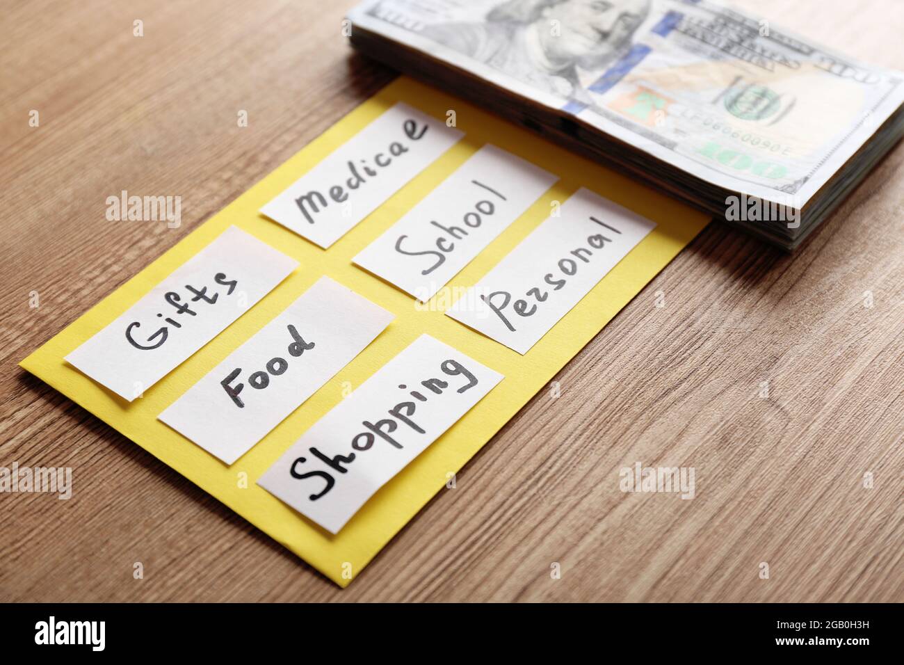 List of needs and cash on wooden background Stock Photo - Alamy