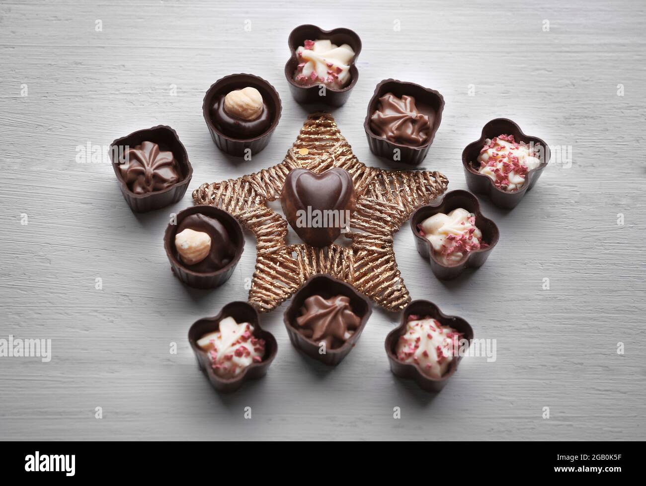 Set of chocolate candies forming star on a light wooden background ...