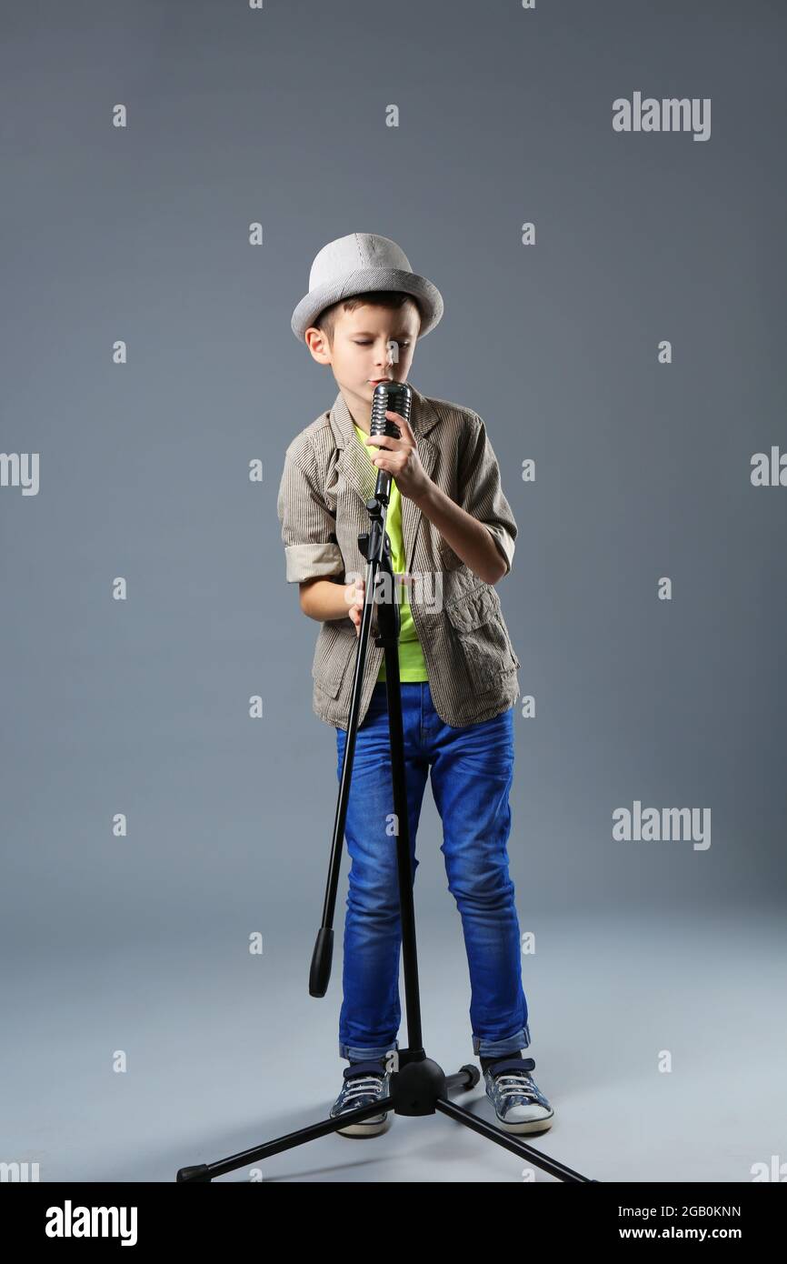 Little boy singing with microphone on a grey background Stock Photo - Alamy