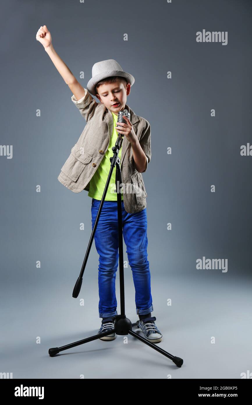 Little boy singing with microphone on a grey background Stock Photo - Alamy