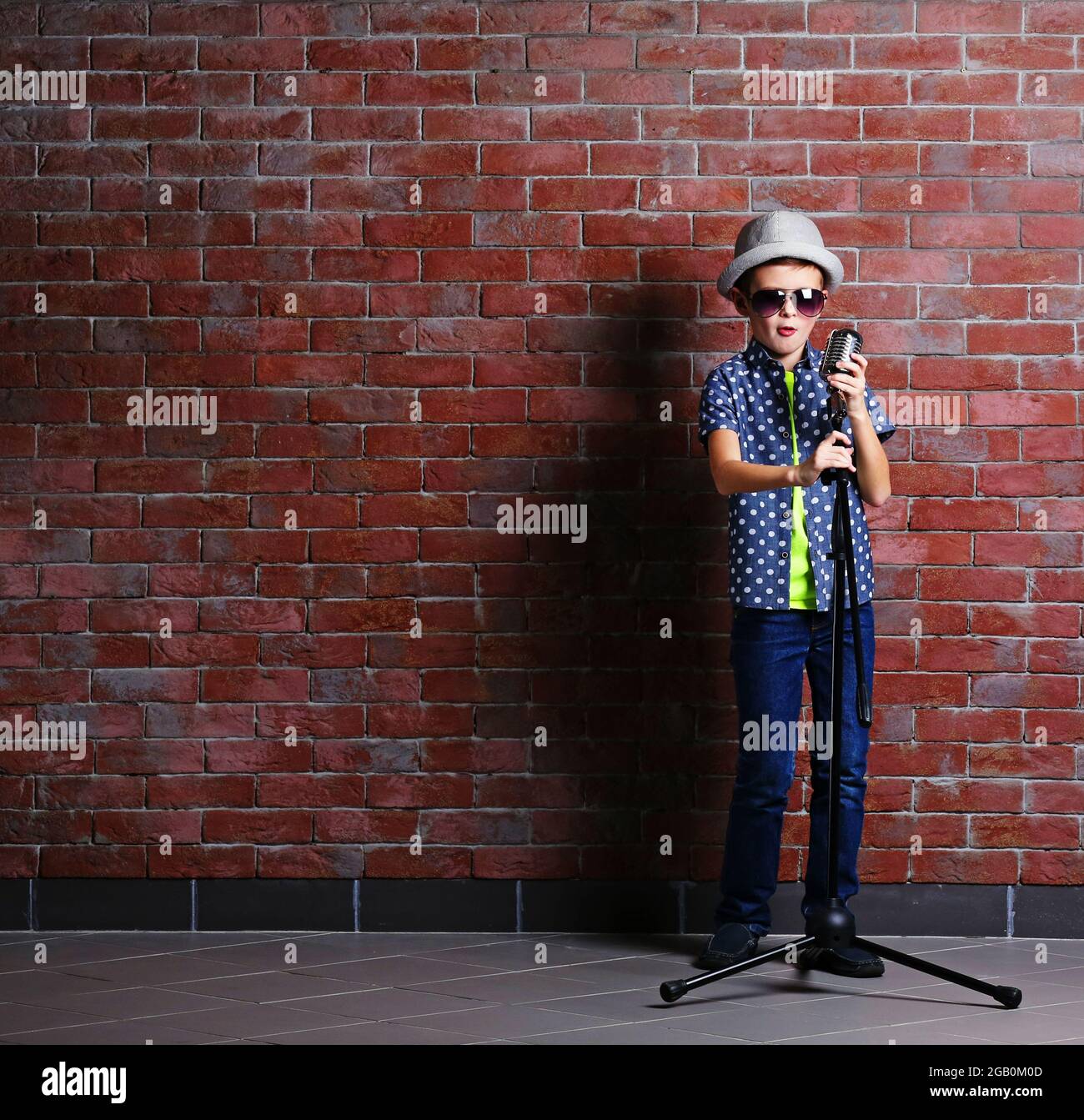 Little boy singing with microphone on a brick wall background Stock ...