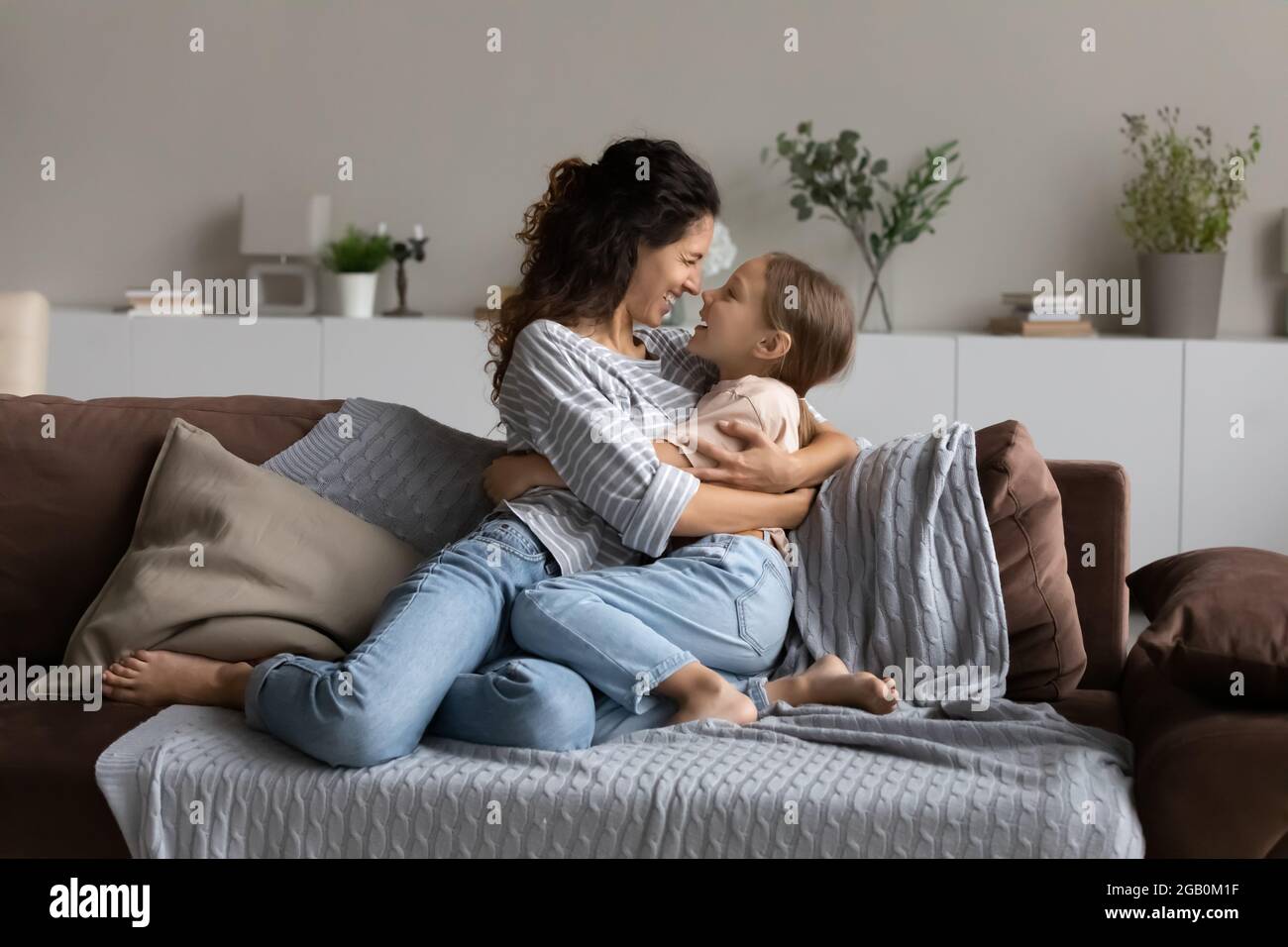 Happy mom and little daughter girl hugging, resting on couch Stock ...