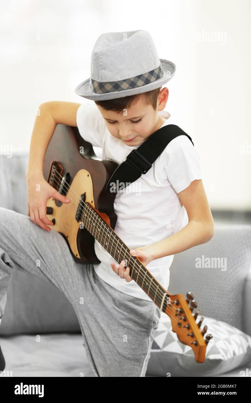 Little boy playing guitar on a sofa at home Stock Photo - Alamy