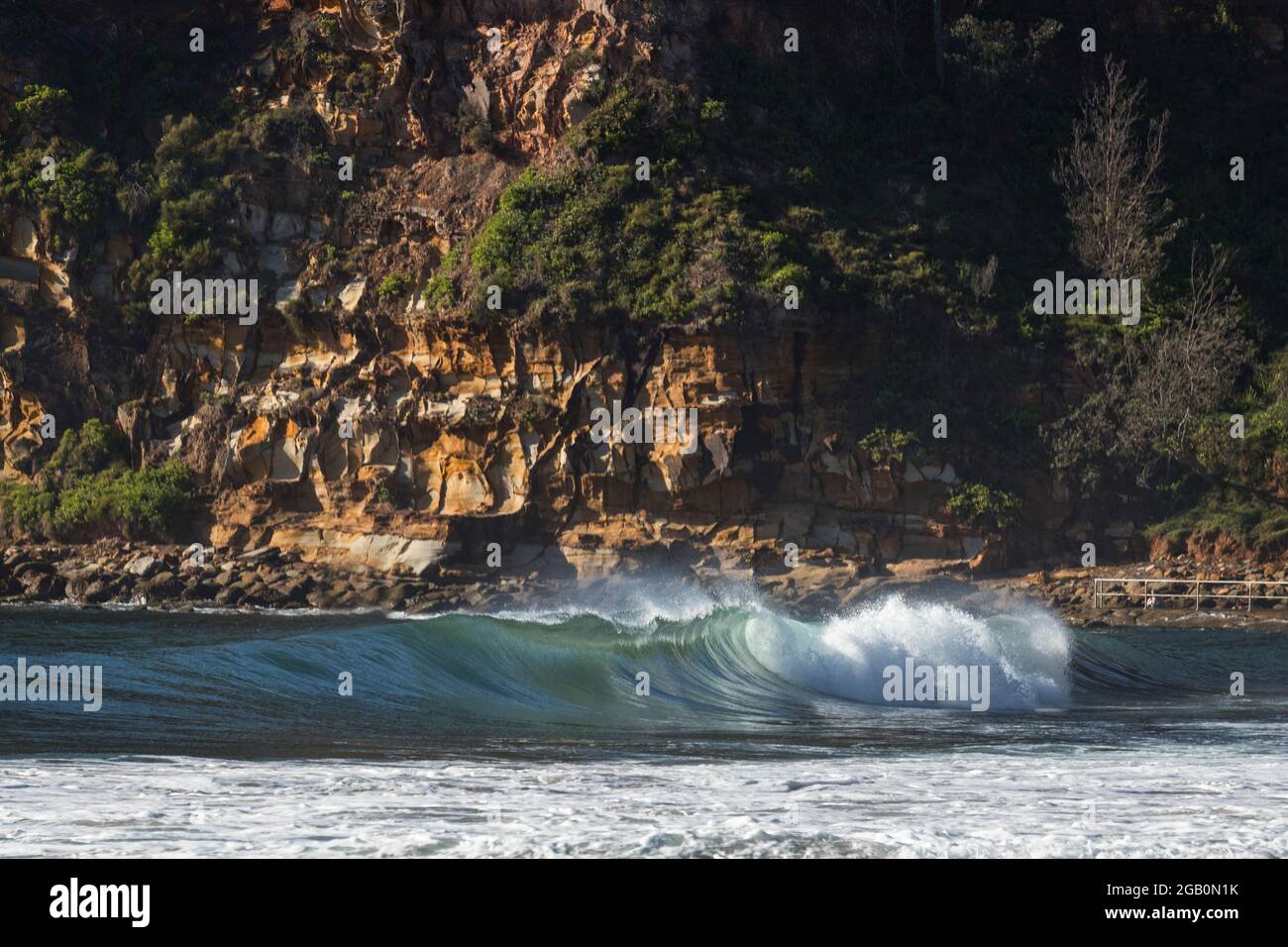 wave breaking at the beach in front of rock wall Stock Photo - Alamy
