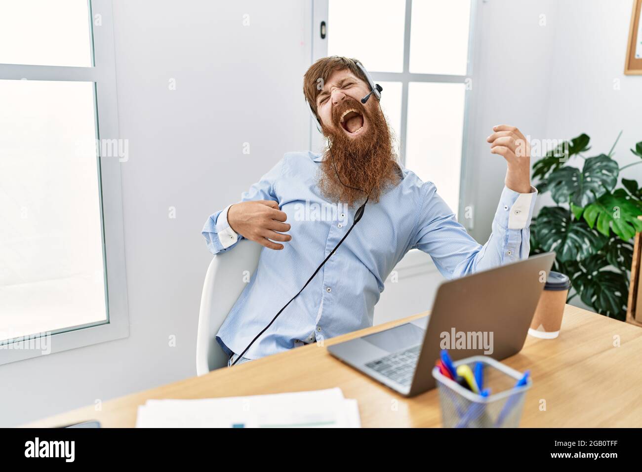 Young irish call center agent smiling listening to music doing guitar ...