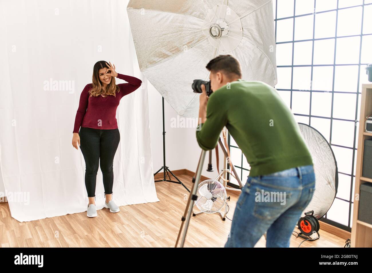 Young woman at photography studio smiling happy doing ok sign with hand ...