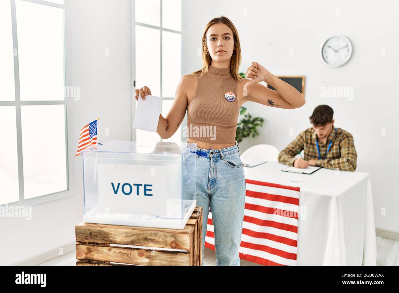 Young blonde girl voting putting envelop in ballot box with angry face ...