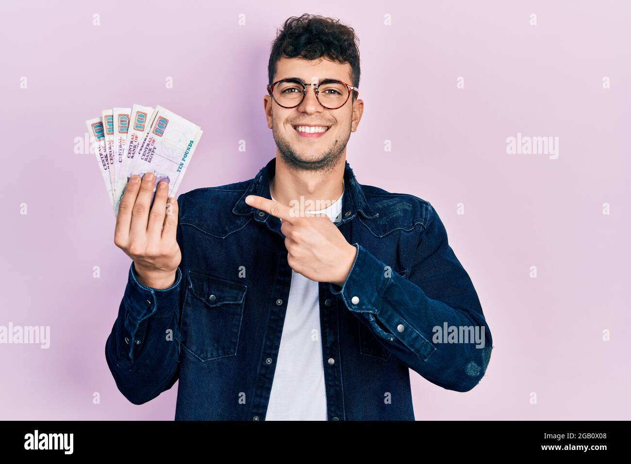 Young hispanic man holding egyptian pounds banknotes smiling happy ...