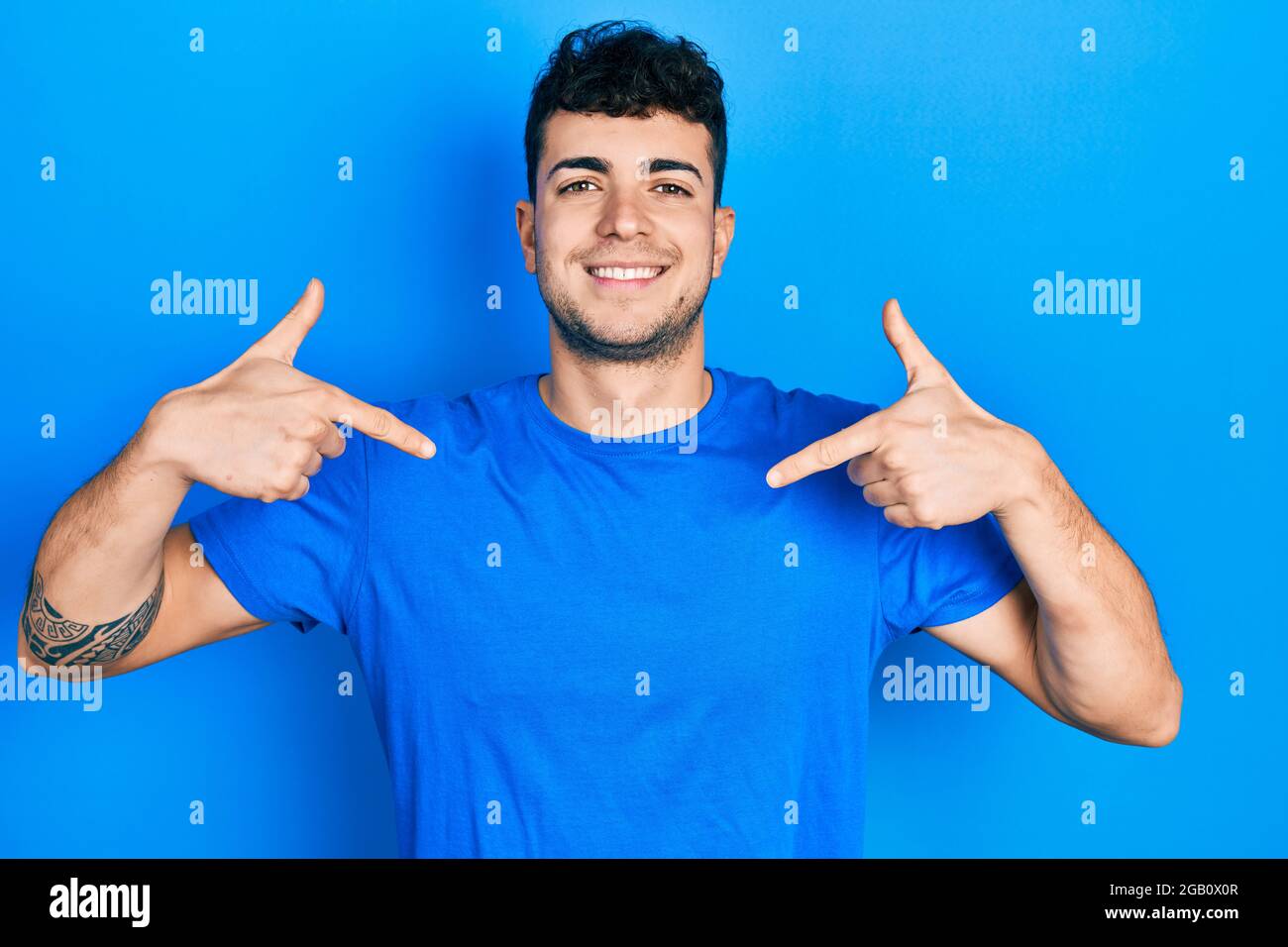 Young hispanic man wearing casual blue t shirt looking confident with ...