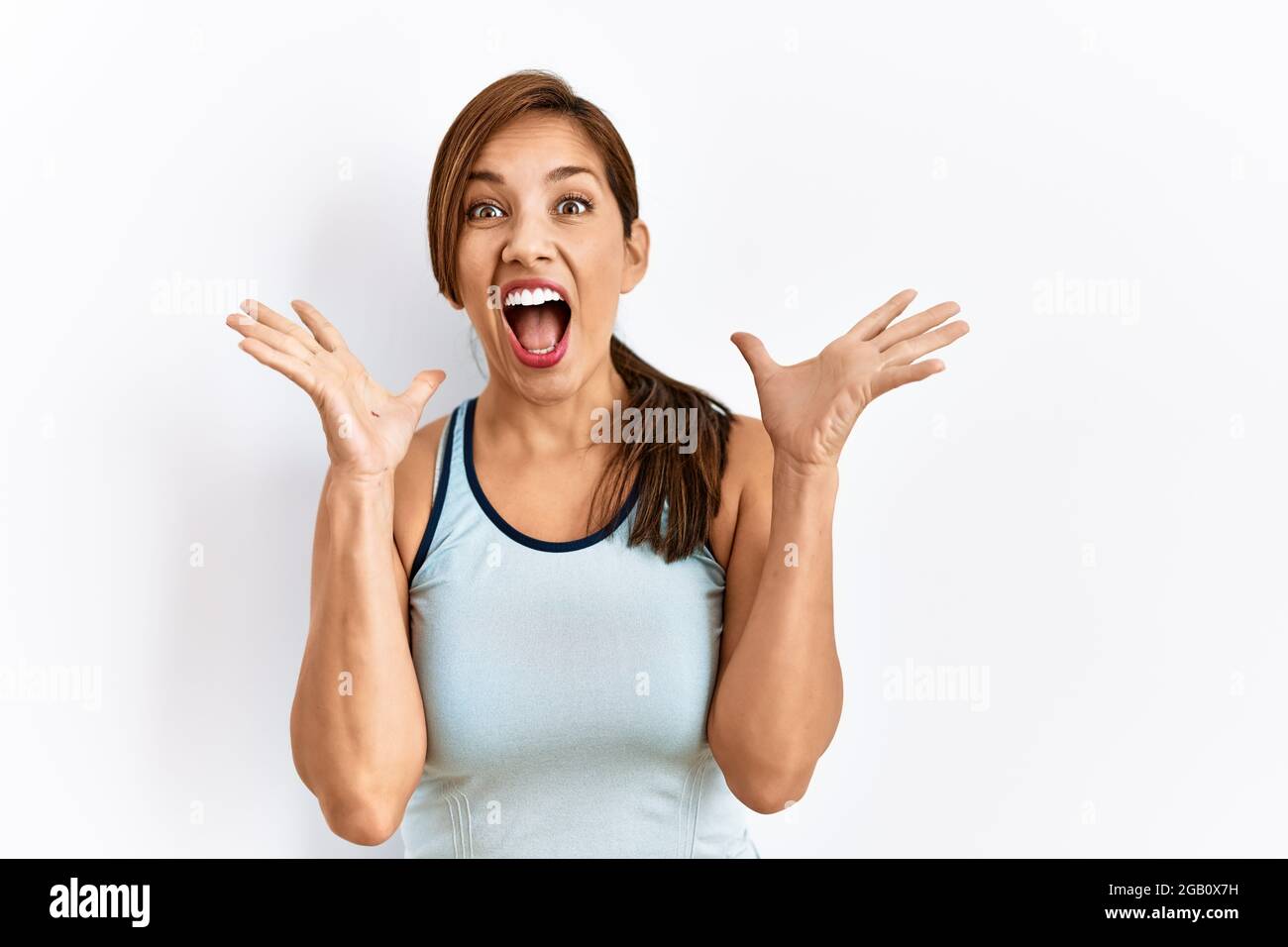 Young latin woman wearing sporty clothes over isolated background ...