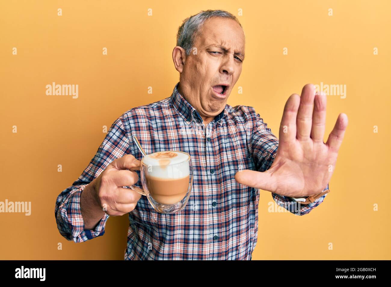 Handsome senior man with grey hair drinking a cup coffee doing stop ...