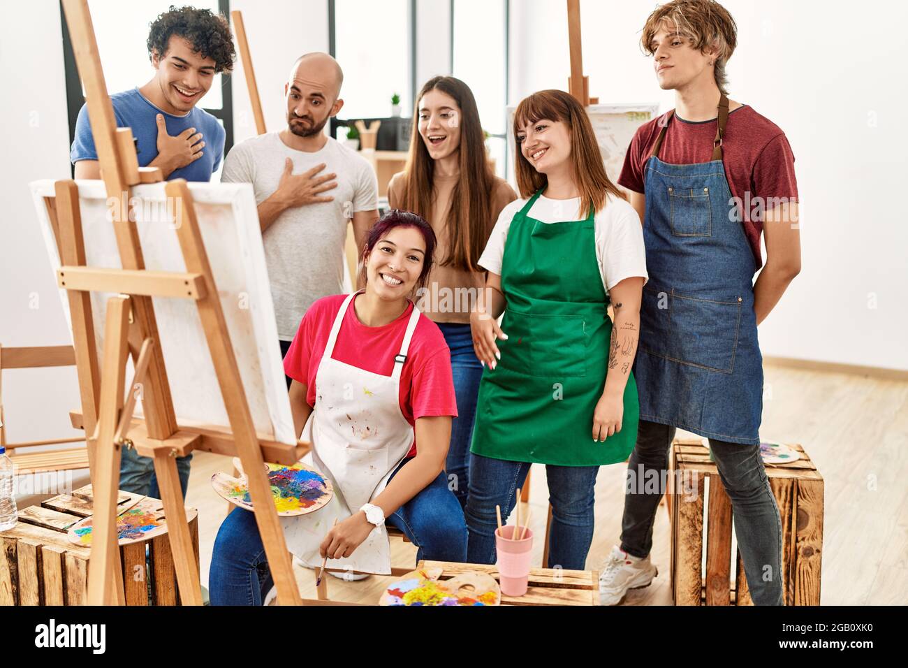 Group of young paint students smiling happy and looking draw of partner ...