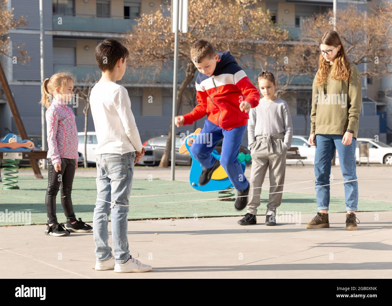 Energetic kids playing and skipping on elastic jumping rope in european ...