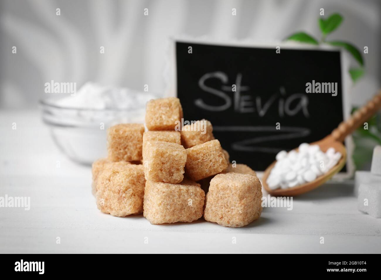 Pile of sugar cubes and stevia on white wooden background Stock Photo ...