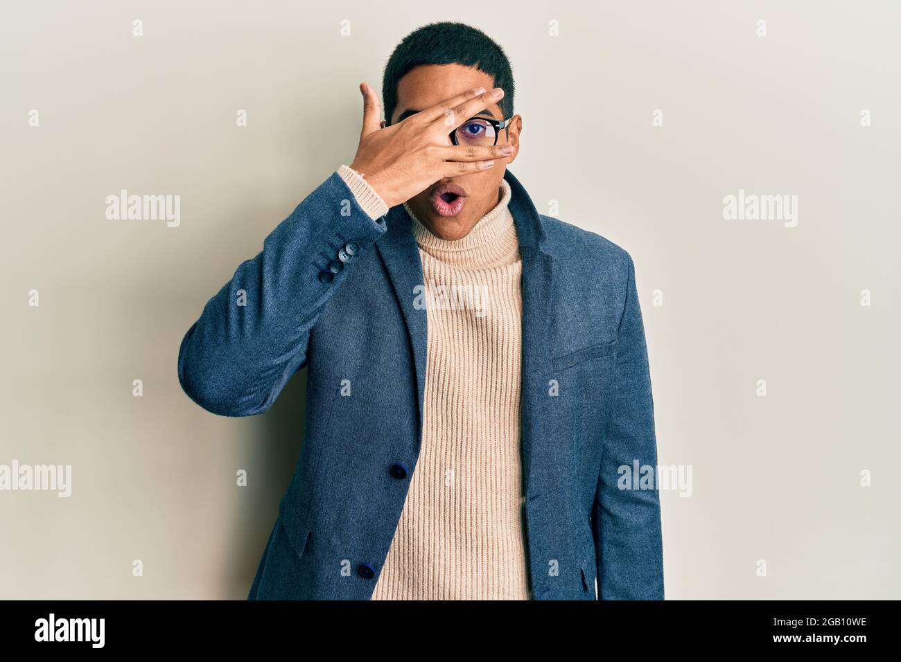 Young handsome hispanic man wearing elegant clothes and glasses peeking ...
