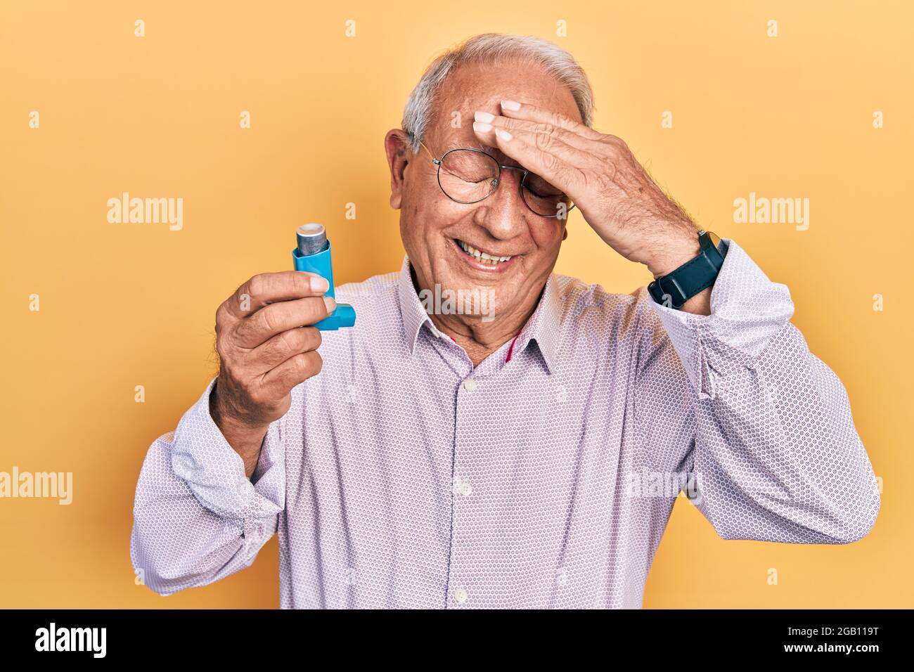 Senior man with grey hair holding medical asthma inhaler stressed and ...