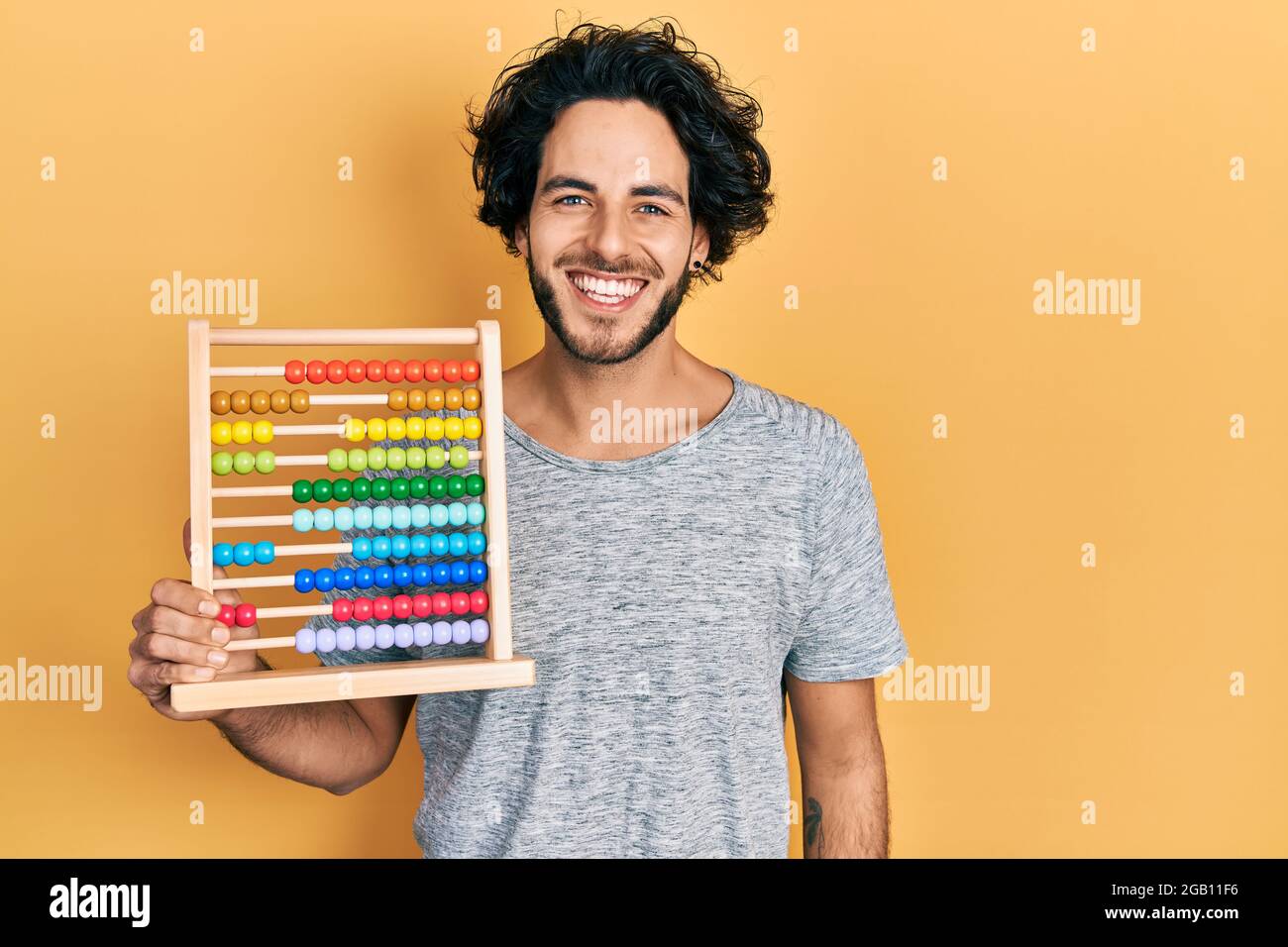 Handsome hispanic man holding traditional abacus looking positive and ...