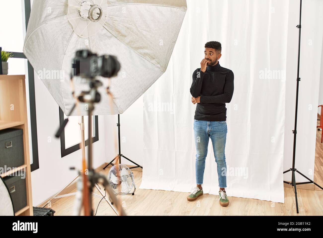 Young hispanic man with beard posing as model at photography studio ...