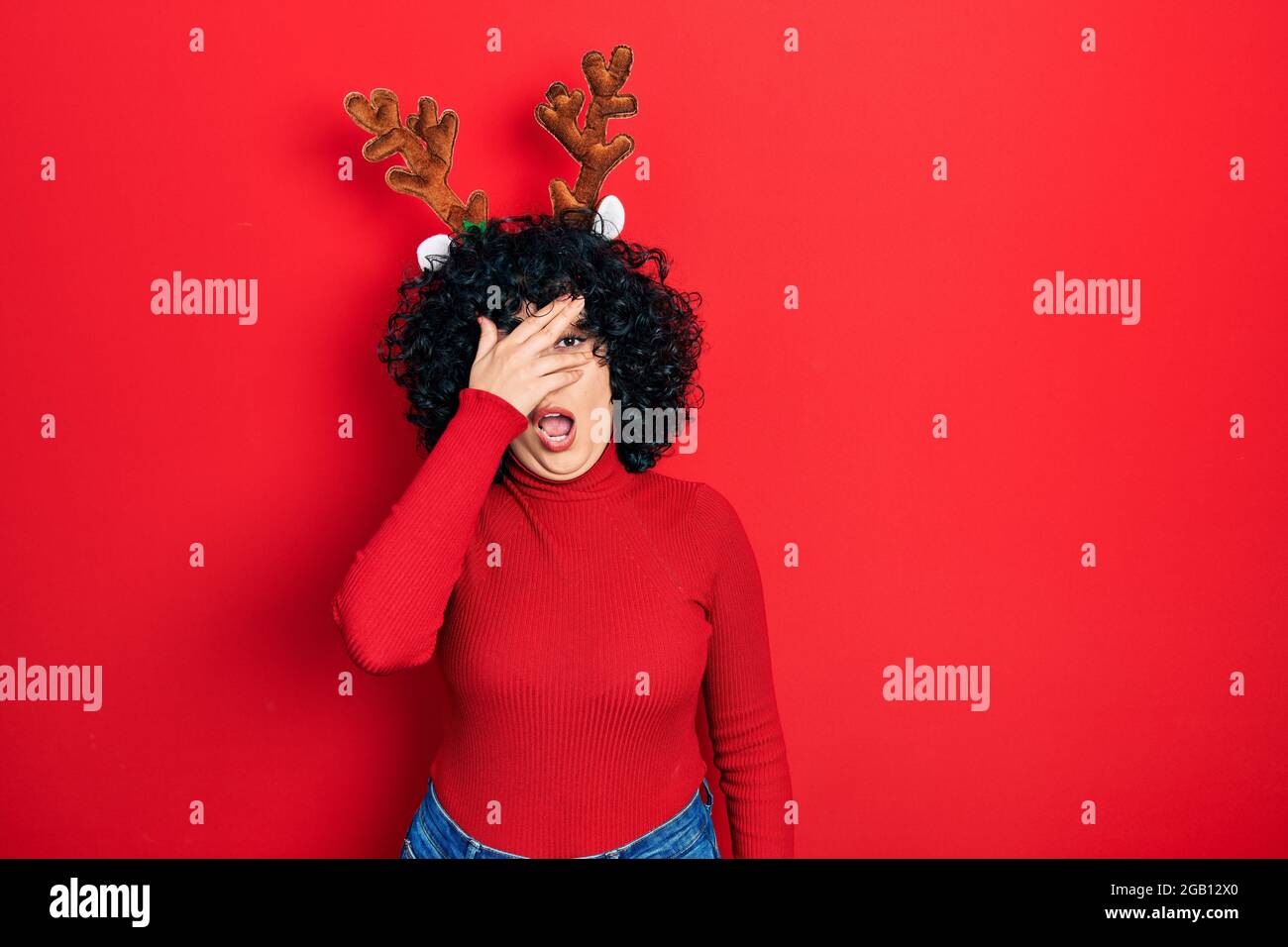 Young middle east woman wearing cute christmas reindeer horns peeking ...