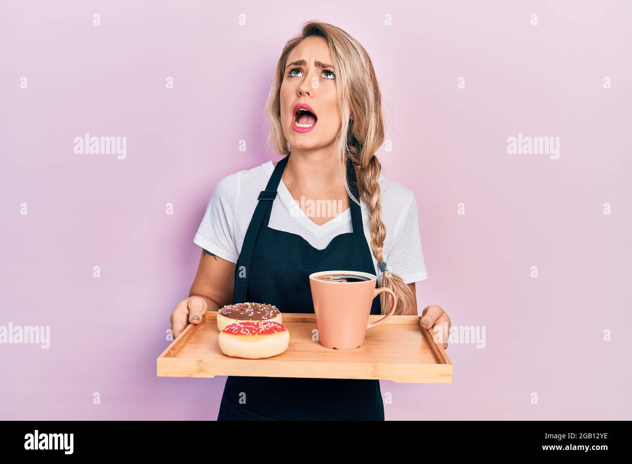 Beautiful young blonde woman wearing waitress apron holding breakfast ...