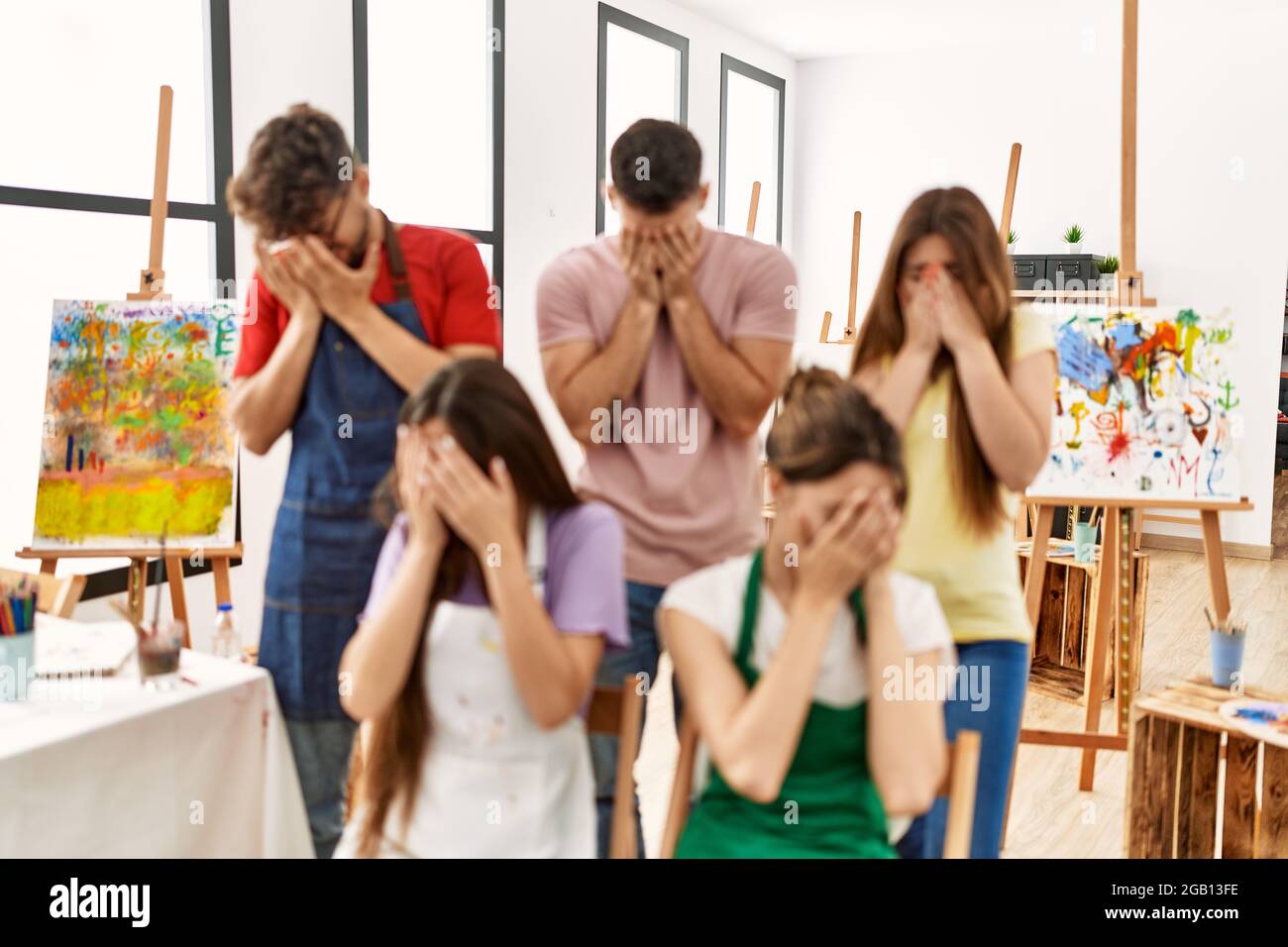 Group of five hispanic artists at art studio with sad expression ...
