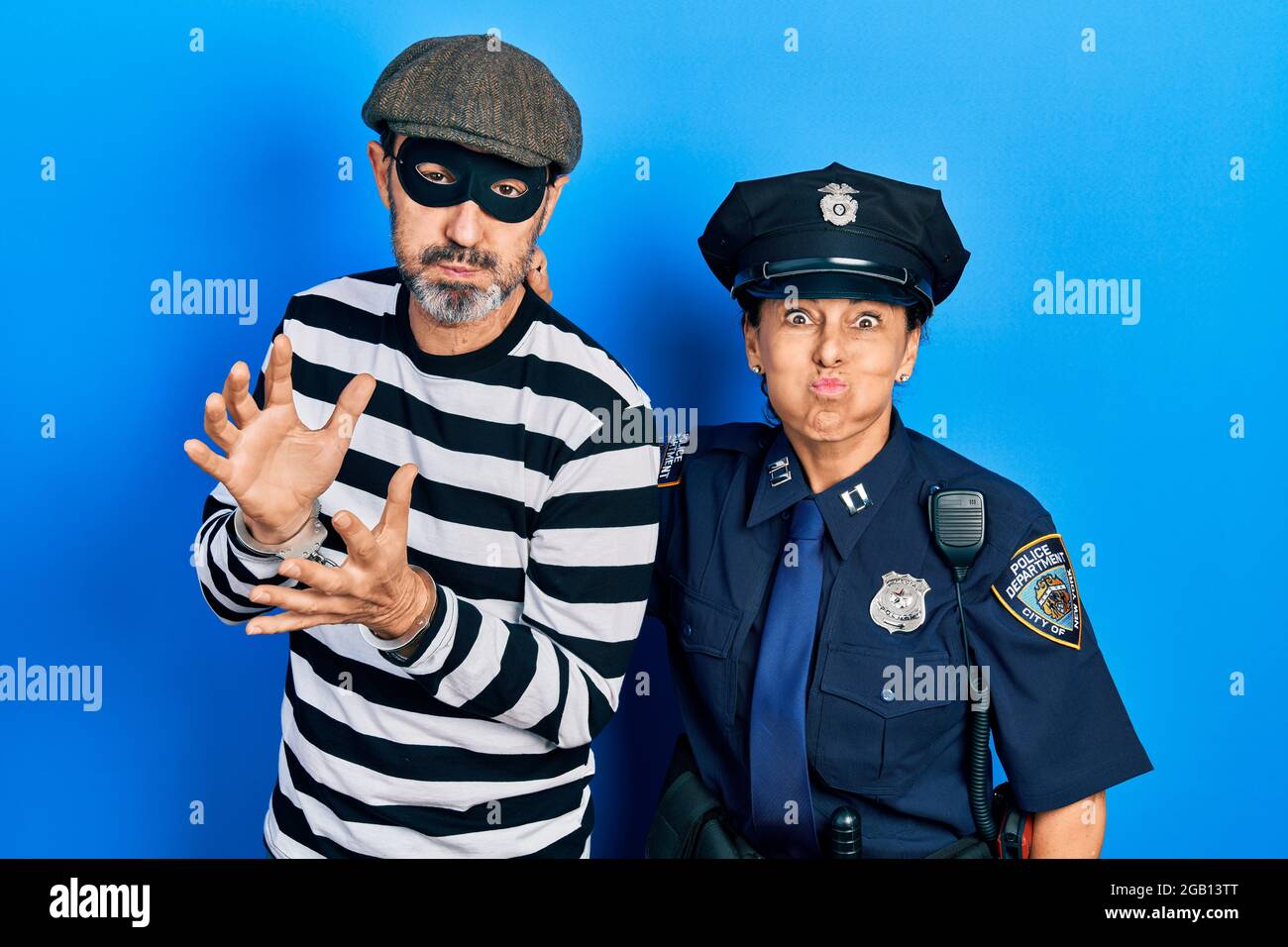 Middle age couple of hispanic woman and man wearing thief and police ...