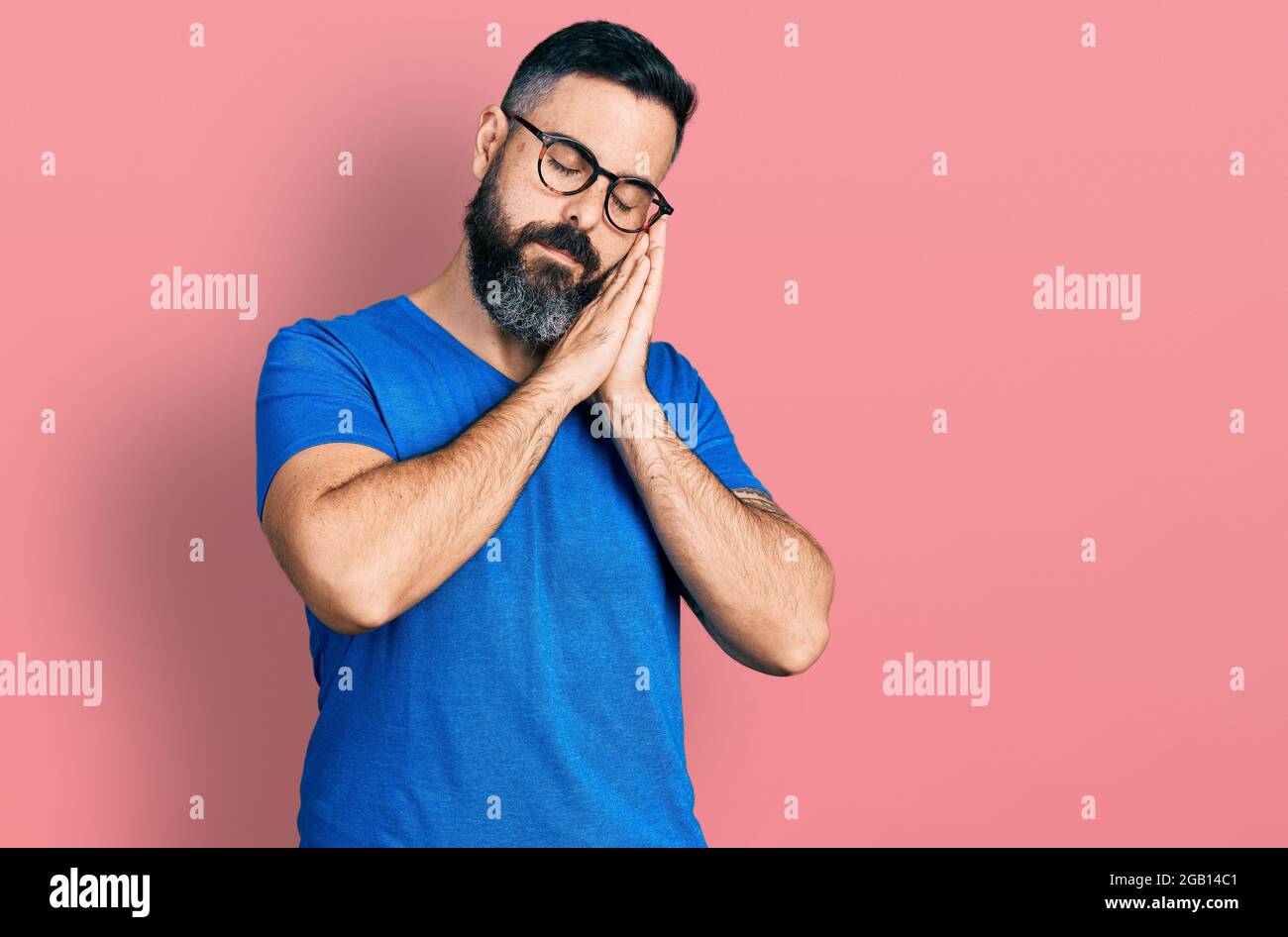 Hispanic man with beard wearing casual t shirt and glasses sleeping ...