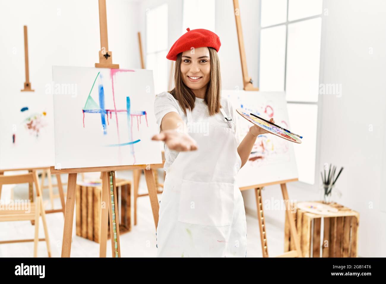 Young artist woman painting on a canvas at art studio smiling cheerful ...