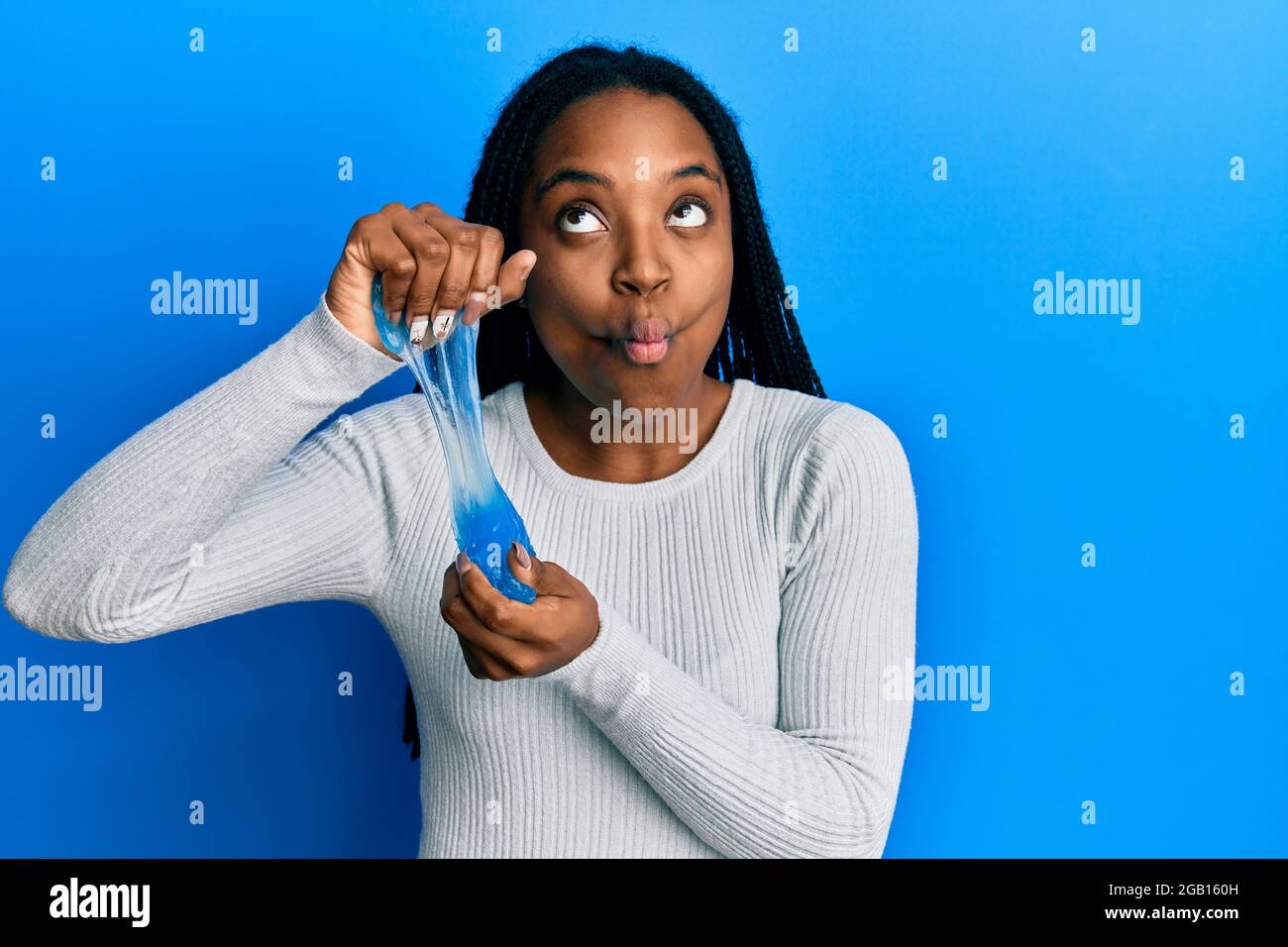 African american woman with braided hair holding slime making fish face ...