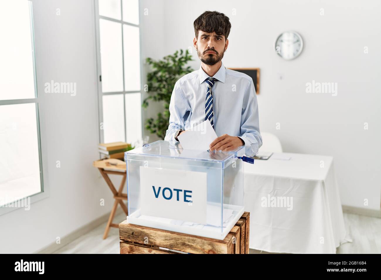 Hispanic man with beard voting putting envelop in ballot box depressed ...