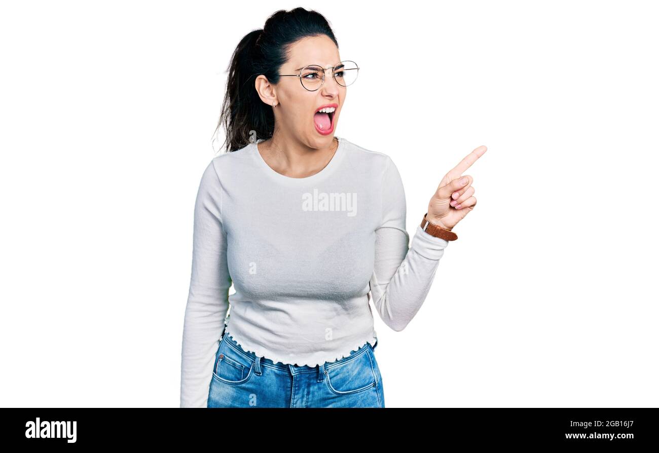 Young hispanic woman pointing with fingers to the side angry and mad screaming frustrated and ...