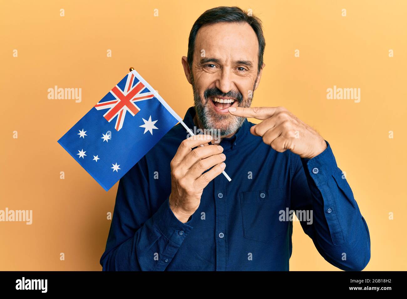 Middle age hispanic man holding australian flag smiling happy pointing ...