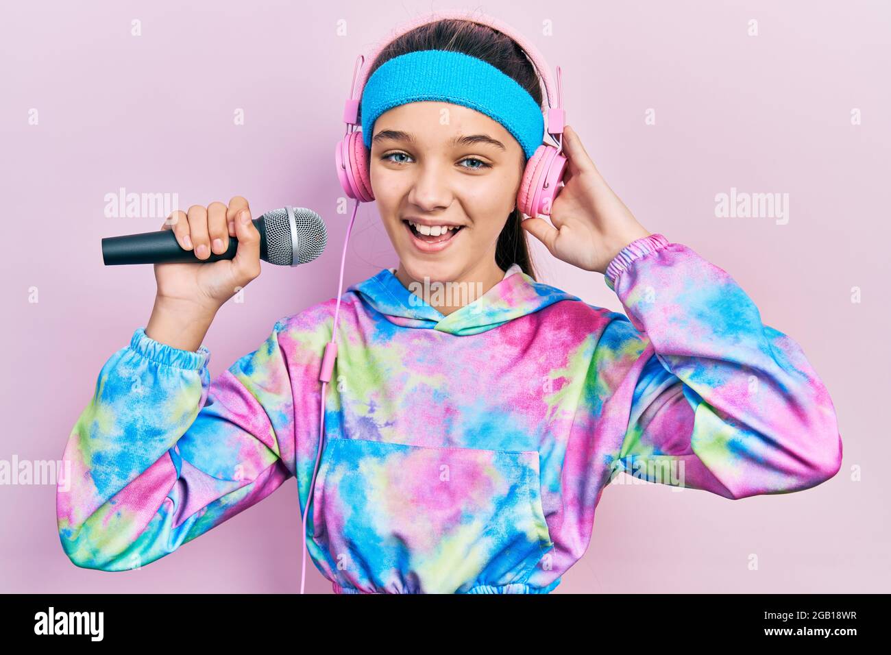 Young brunette girl singing song using microphone wearing sportswear ...