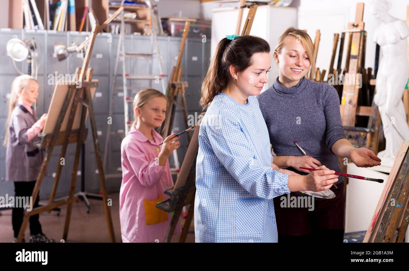 Female teacher helping girl during painting class Stock Photo - Alamy