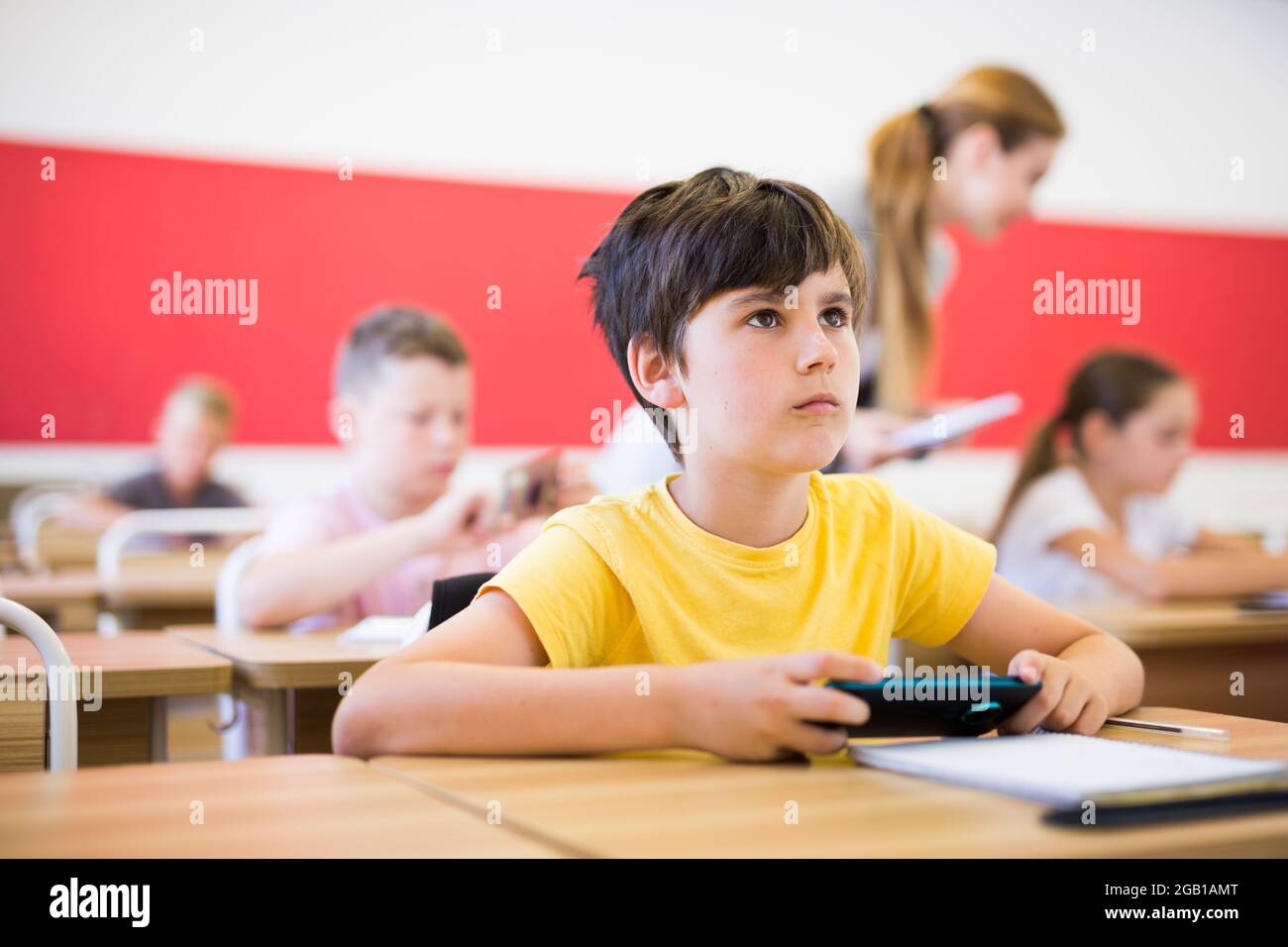 Focused tween schoolboy using mobile phone at lesson in class Stock ...