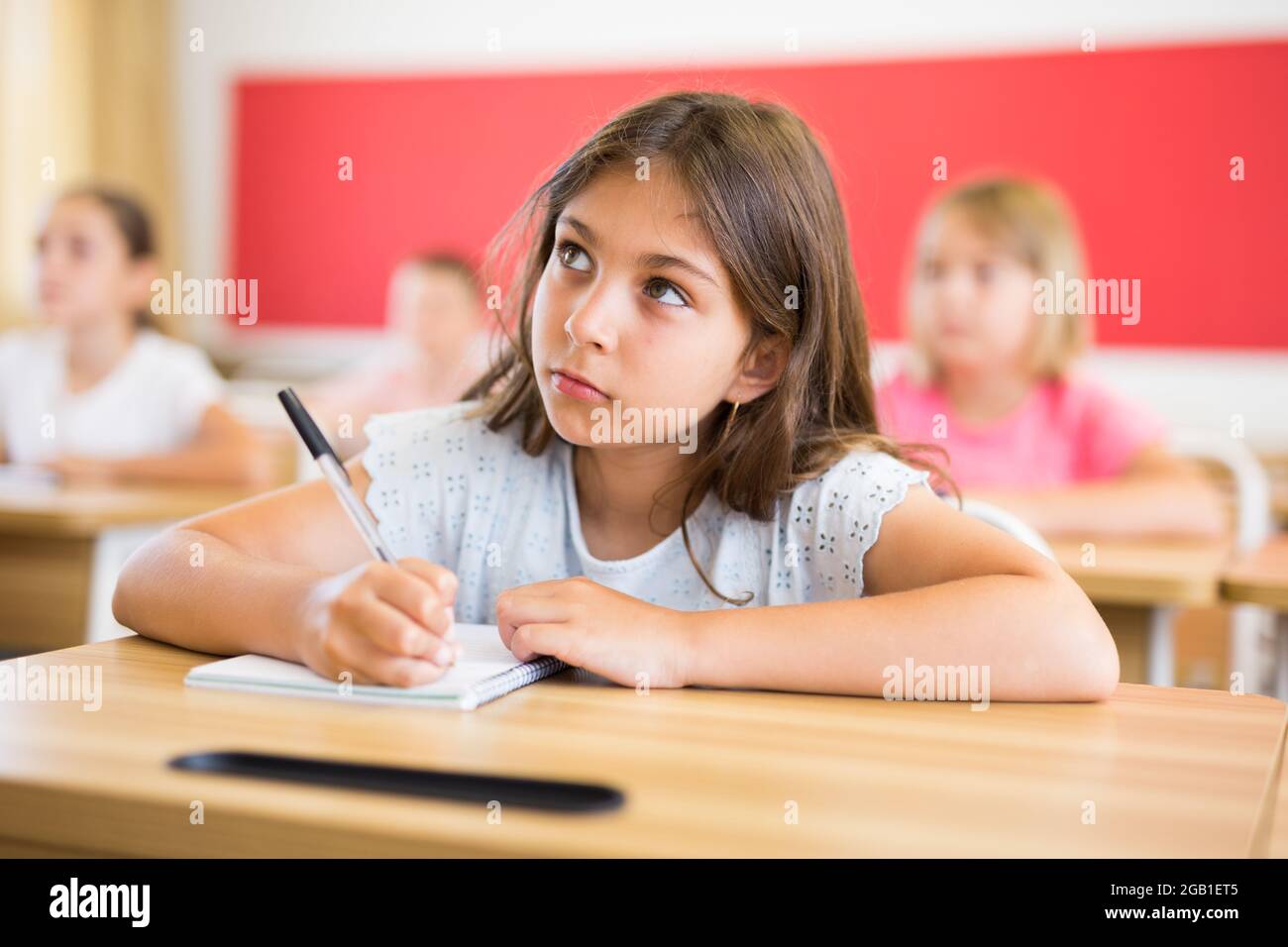 Schoolgirl sitting in classroom during lesson in elementary school ...